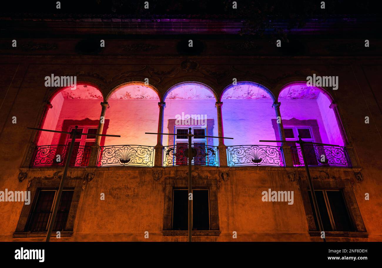 The exterior of old stone building with colorful illuminated arch ...