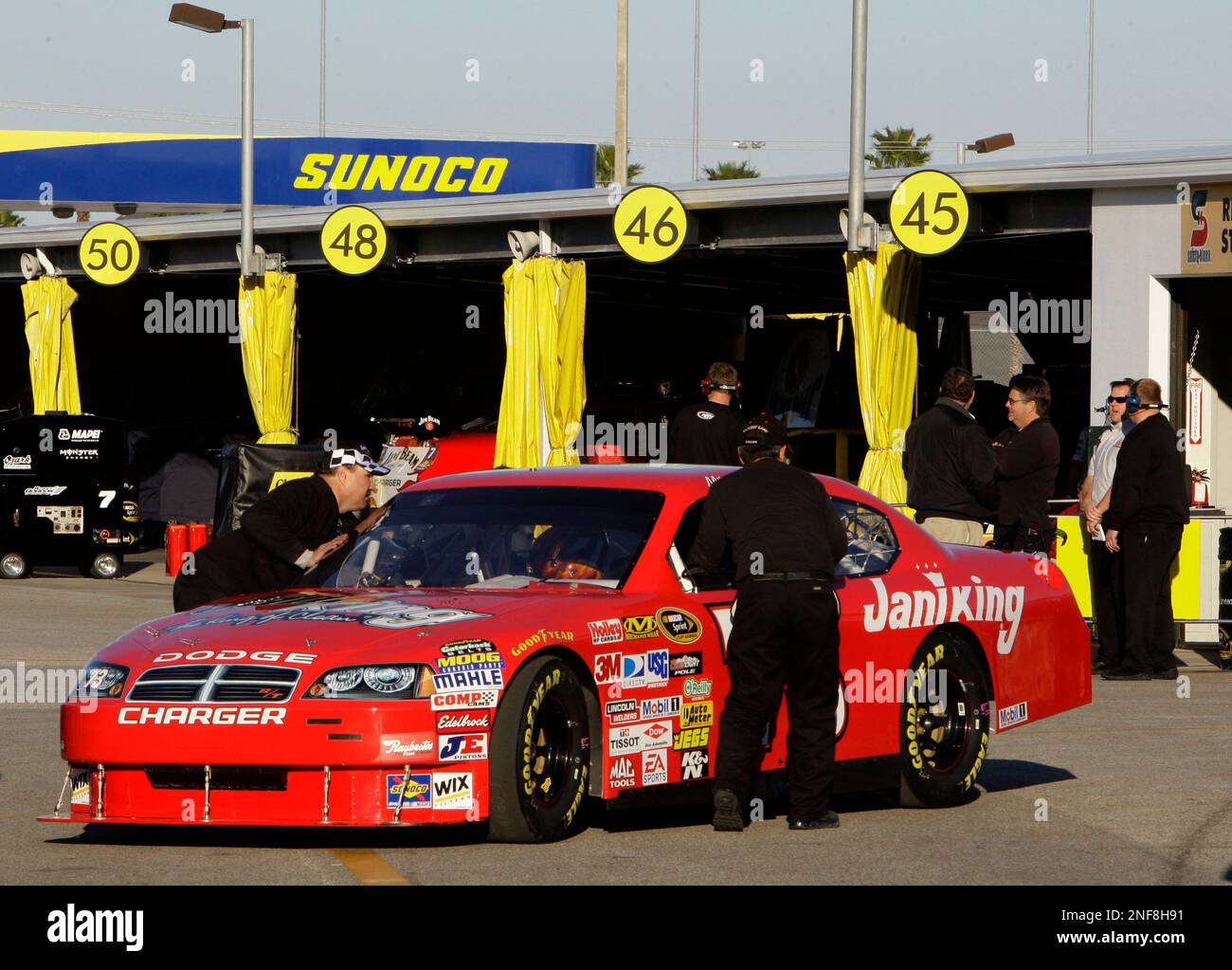 The crew for NASCAR driver Mike Garvey pushes his car back in the ...