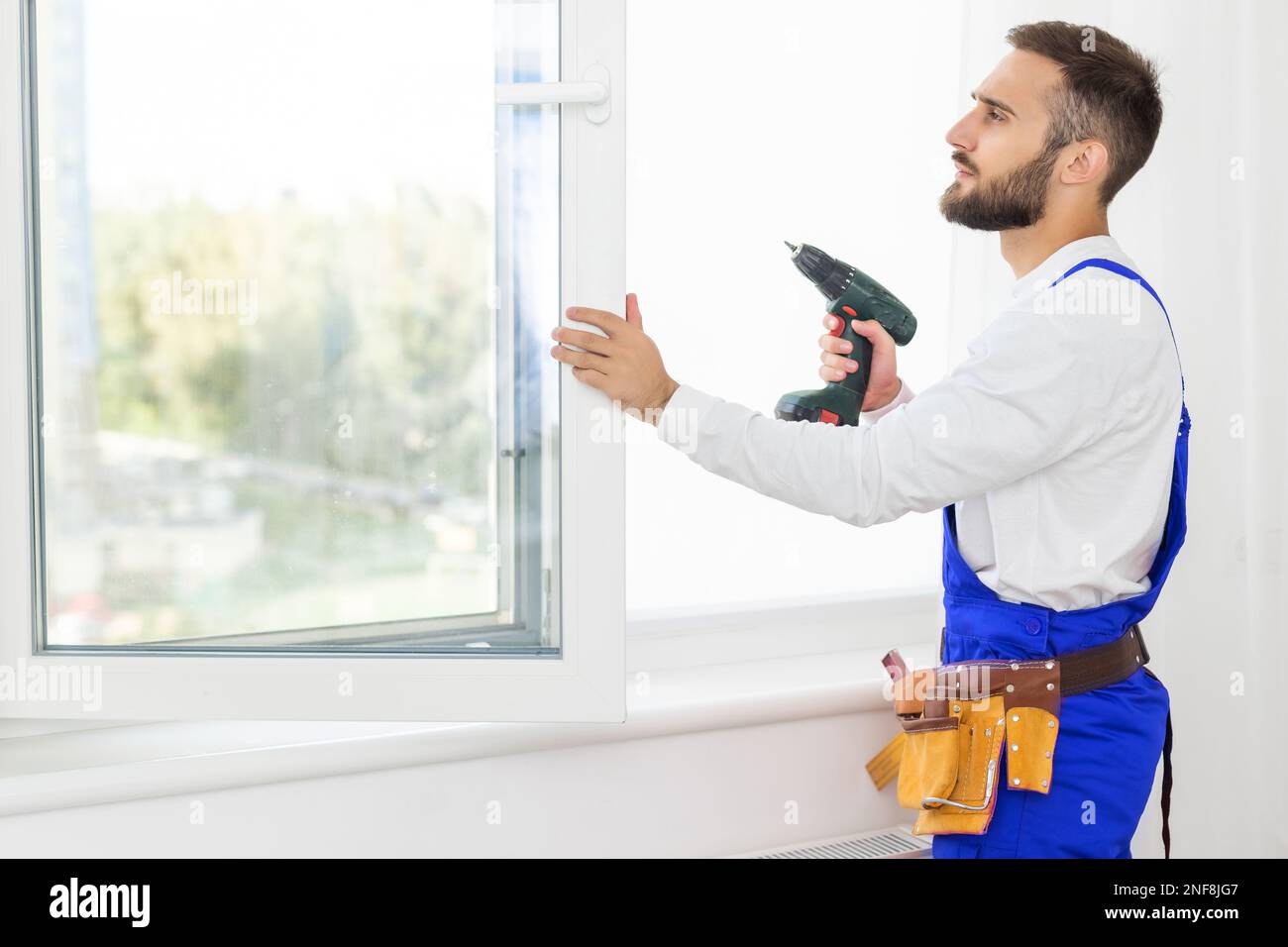 handsome young man installing bay window in a new house construction ...
