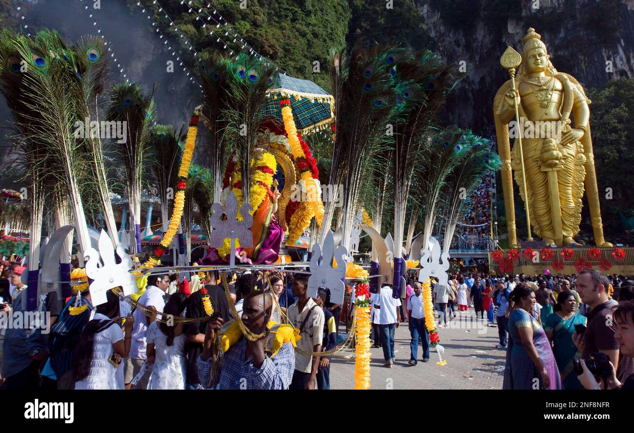 Near the foothills of the temple Hindu devotees carry a "kavadi" down ...