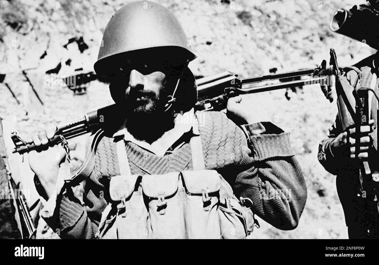 An Afghan guerrilla, wearing a captured Soviet army helmet, marches up ...