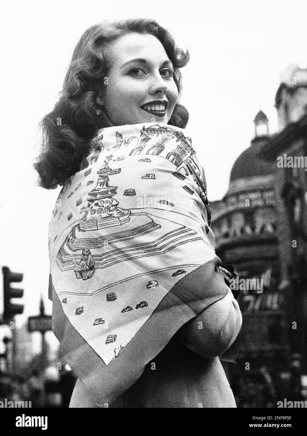 British film star Hazel Court wears a scarf depicting Piccadilly Circus ...