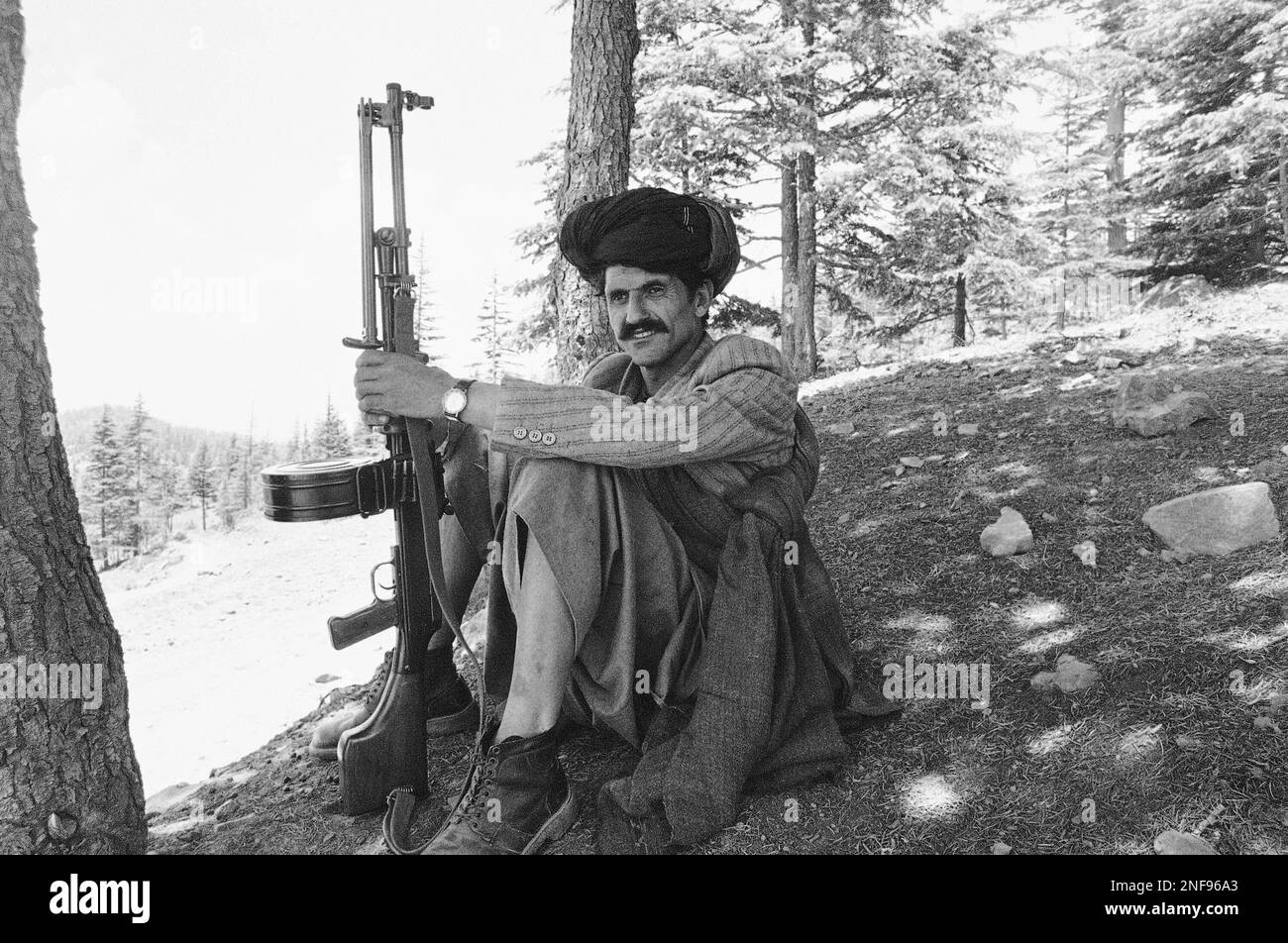An Afghan rebel, armed with a light machine gun, rests after firing ...