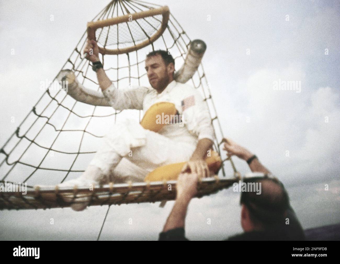 Astronaut James Lovell, Jr. is hoisted in a cage from rubber life raft ...