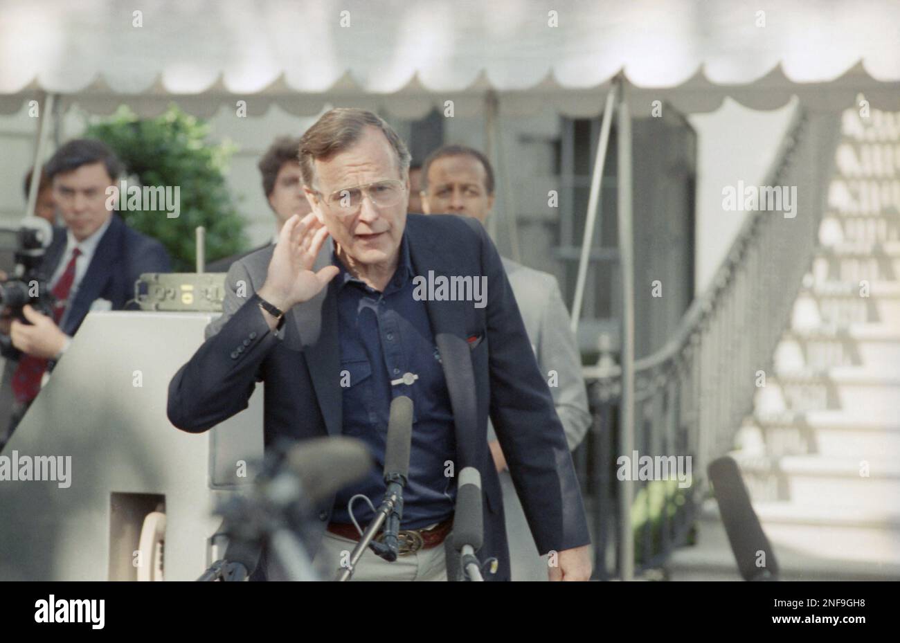 President George H.W. Bush strains to hear reporter's question over the ...
