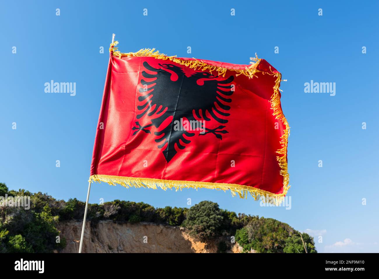 Albania fringed flag. Albanian flag waving on a bright blue sky and island background Stock ...