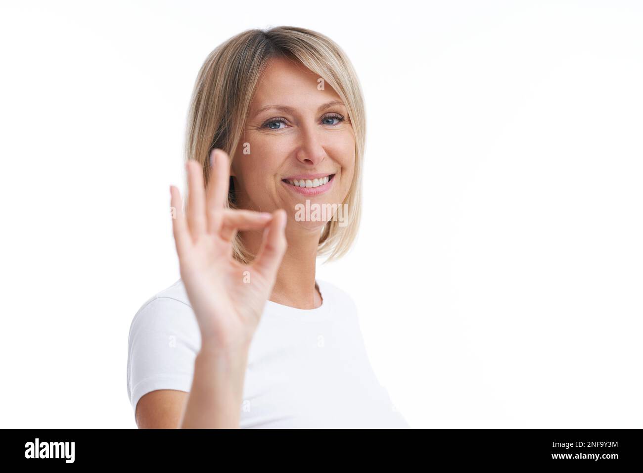 Picture of blonde woman over back isolated background showing ok Stock ...