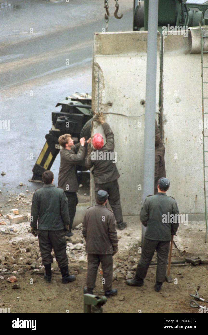 East German border guards take down pieces of the Berlin Wall at ...