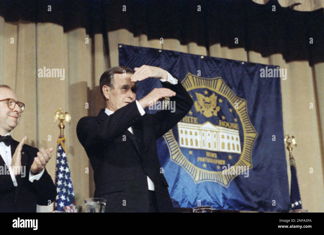 President George Bush shields his eyes from the lights as he scans the ...