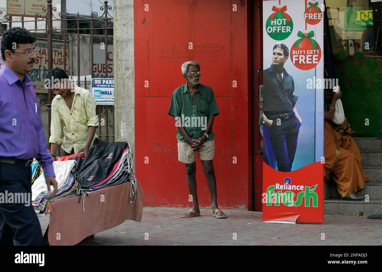 A street vendor arranges his clothes at his stall, left, as a man ...
