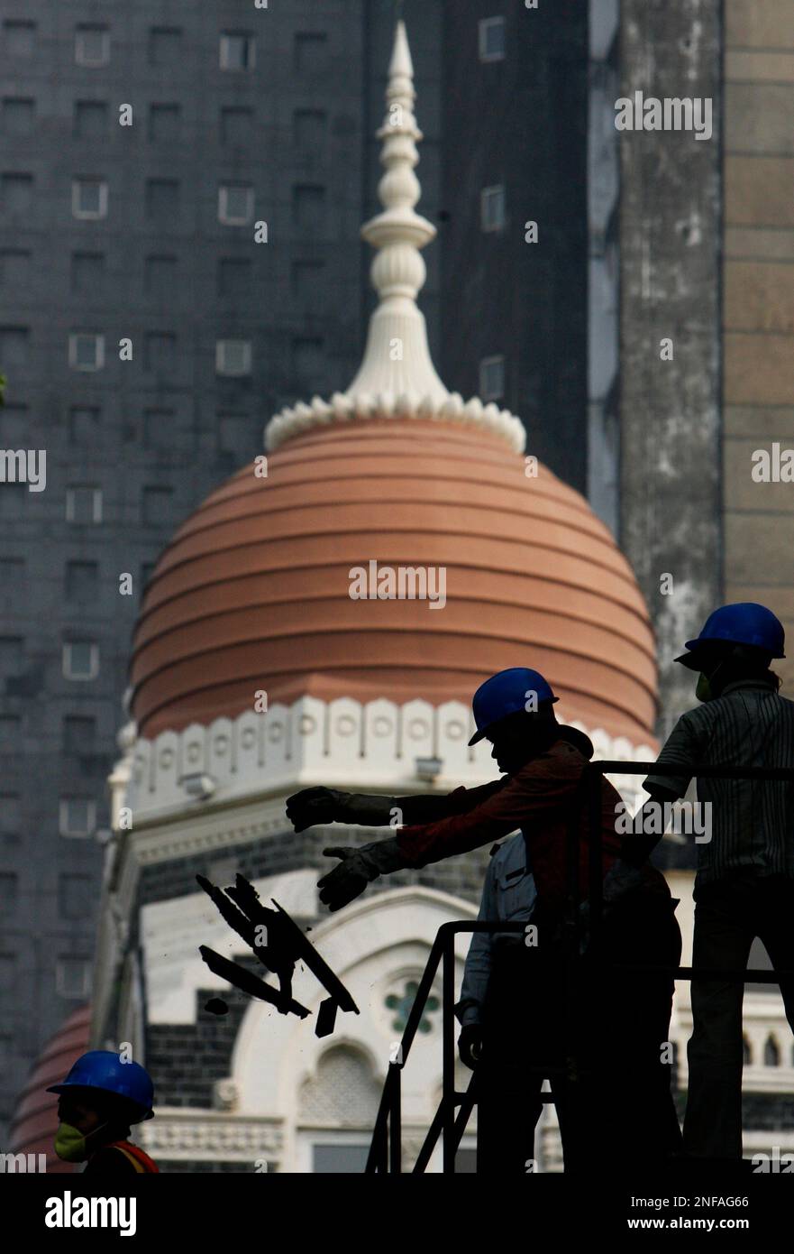 Workmen remove debris from the Taj Mahal Palace and Towers hotel a day ...