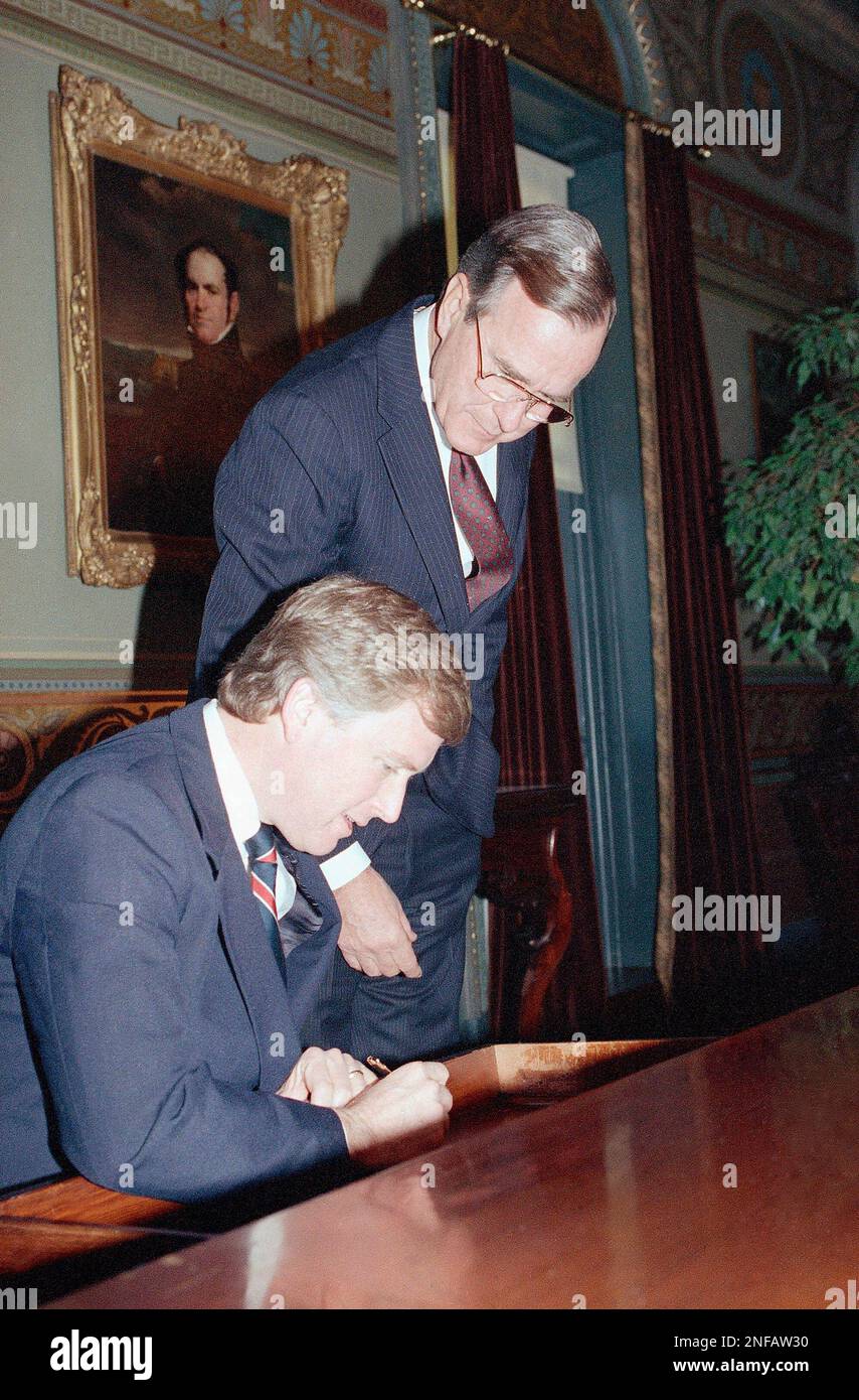 Vice President Dan Quayle, left, signs his name in the drawer of a desk ...