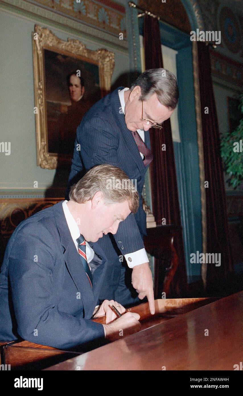 Vice President Dan Quayle, left, signs his name in the drawer of a desk ...
