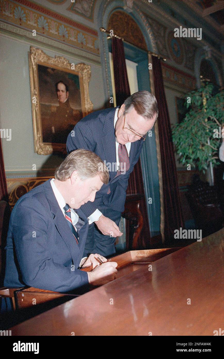 Vice President Dan Quayle, left, signs his name in the drawer of a desk ...