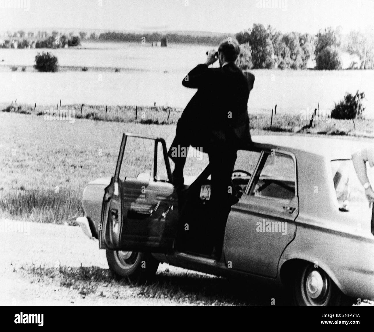 An FBI agent views a Gypsum, Kan., farm home through binoculars ...