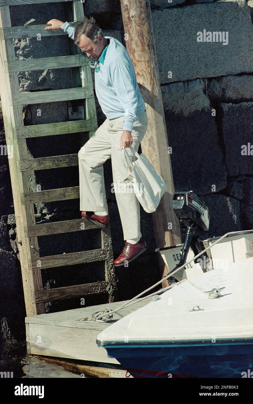President George Bush climbs down a ladder on the bulkhead of his dock ...