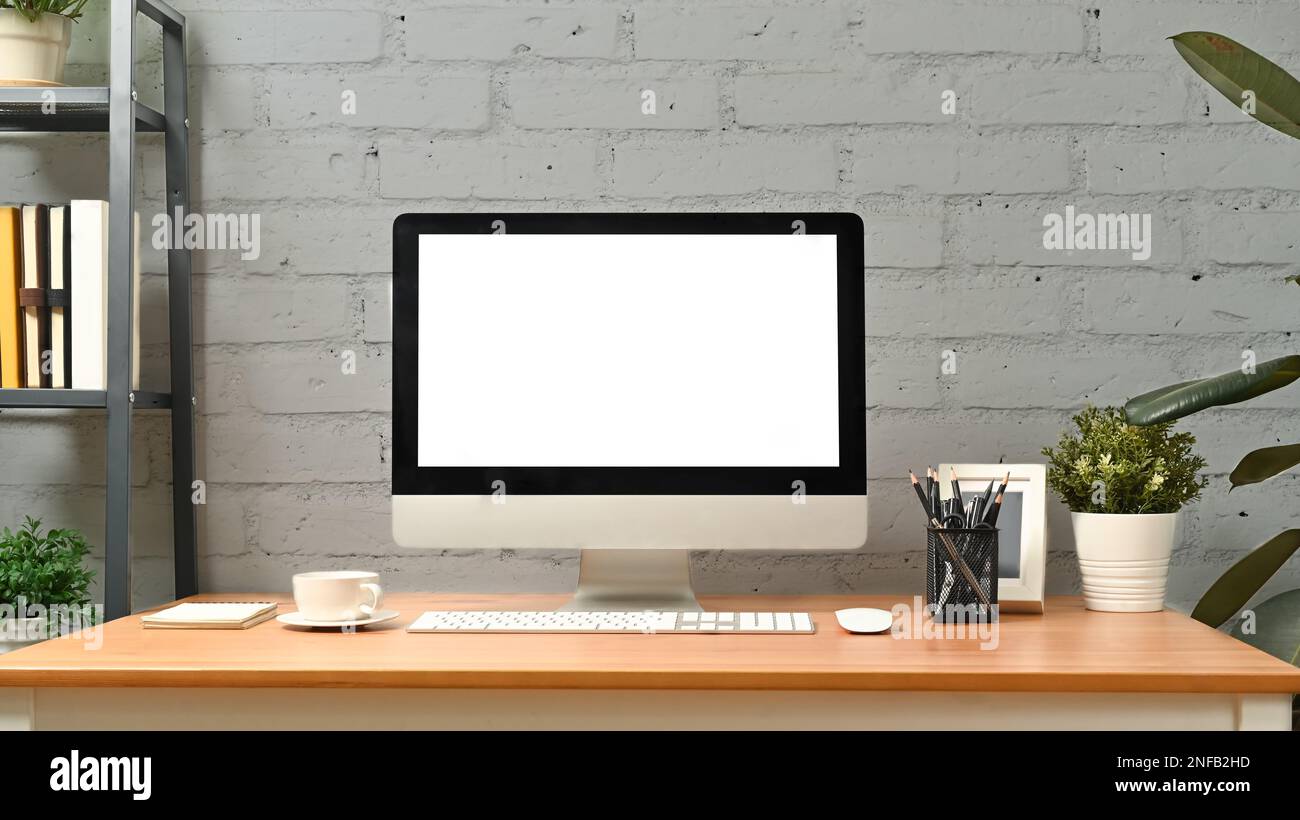 Comfortable workplace with computer and supplies against brick wall ...