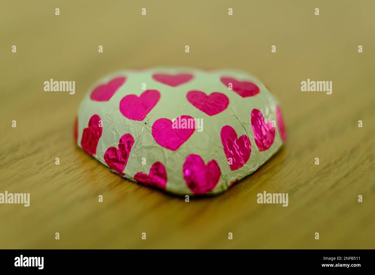 Heart-shaped chocolate candies in shiny paper with red hearts Stock ...