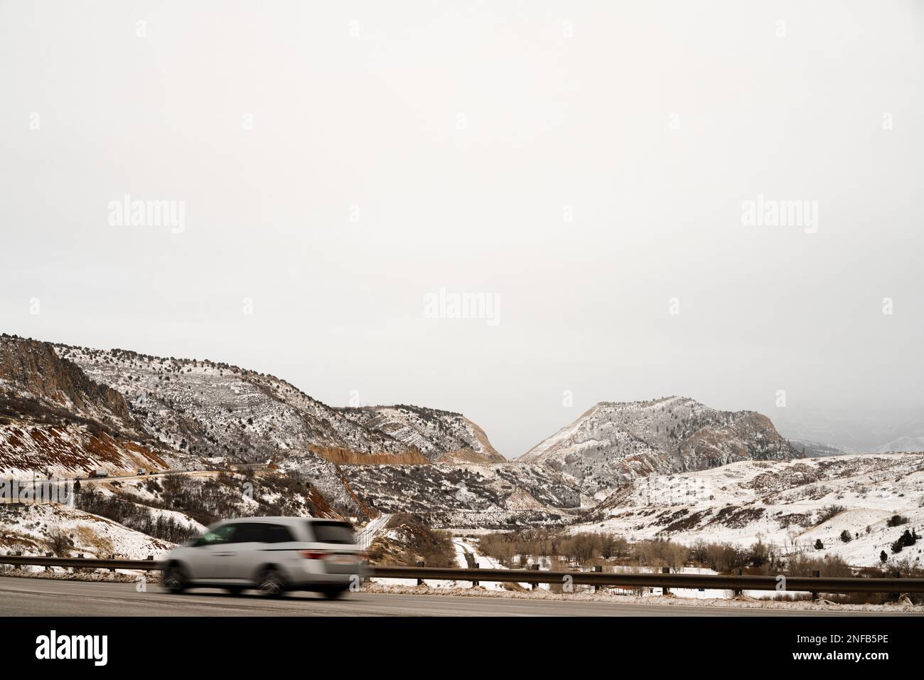 A long-exposure shot of the car driving on the highway with snowy Utah ...