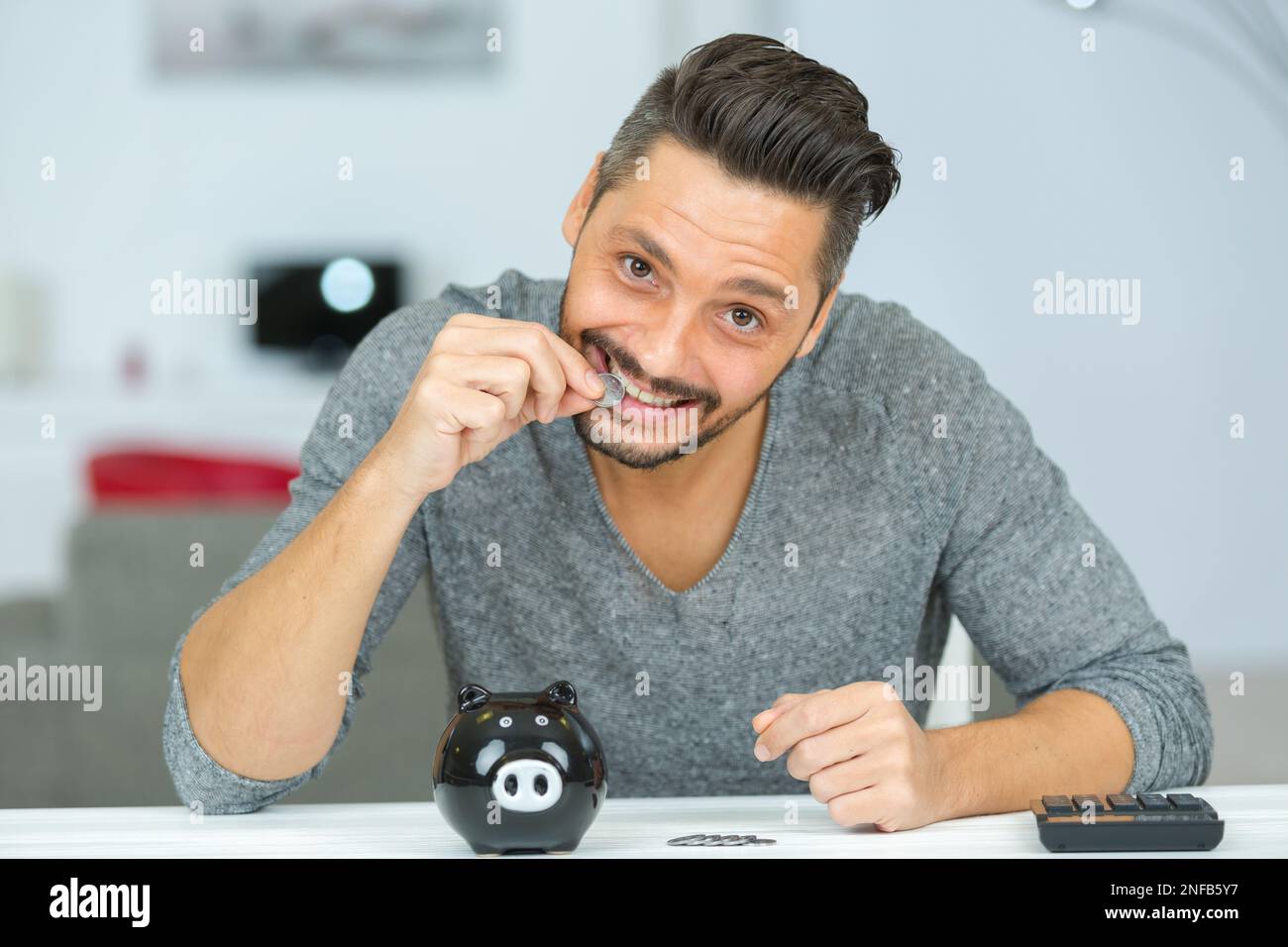 man sitting with piggy bank and biting a coin Stock Photo - Alamy