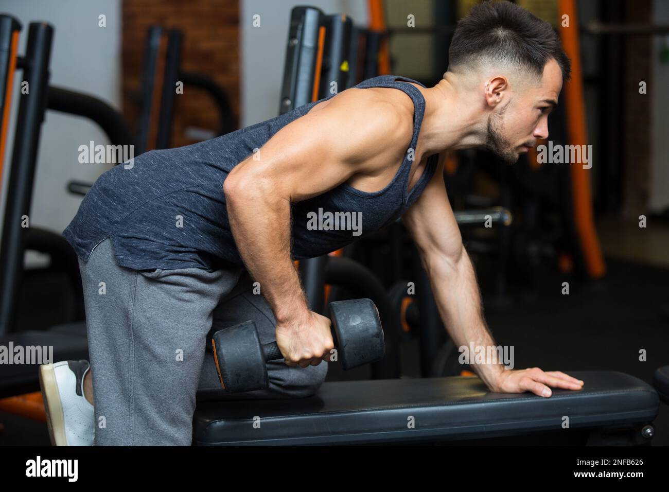 male doing one-arm dumbbell rows on bench in gym Stock Photo - Alamy