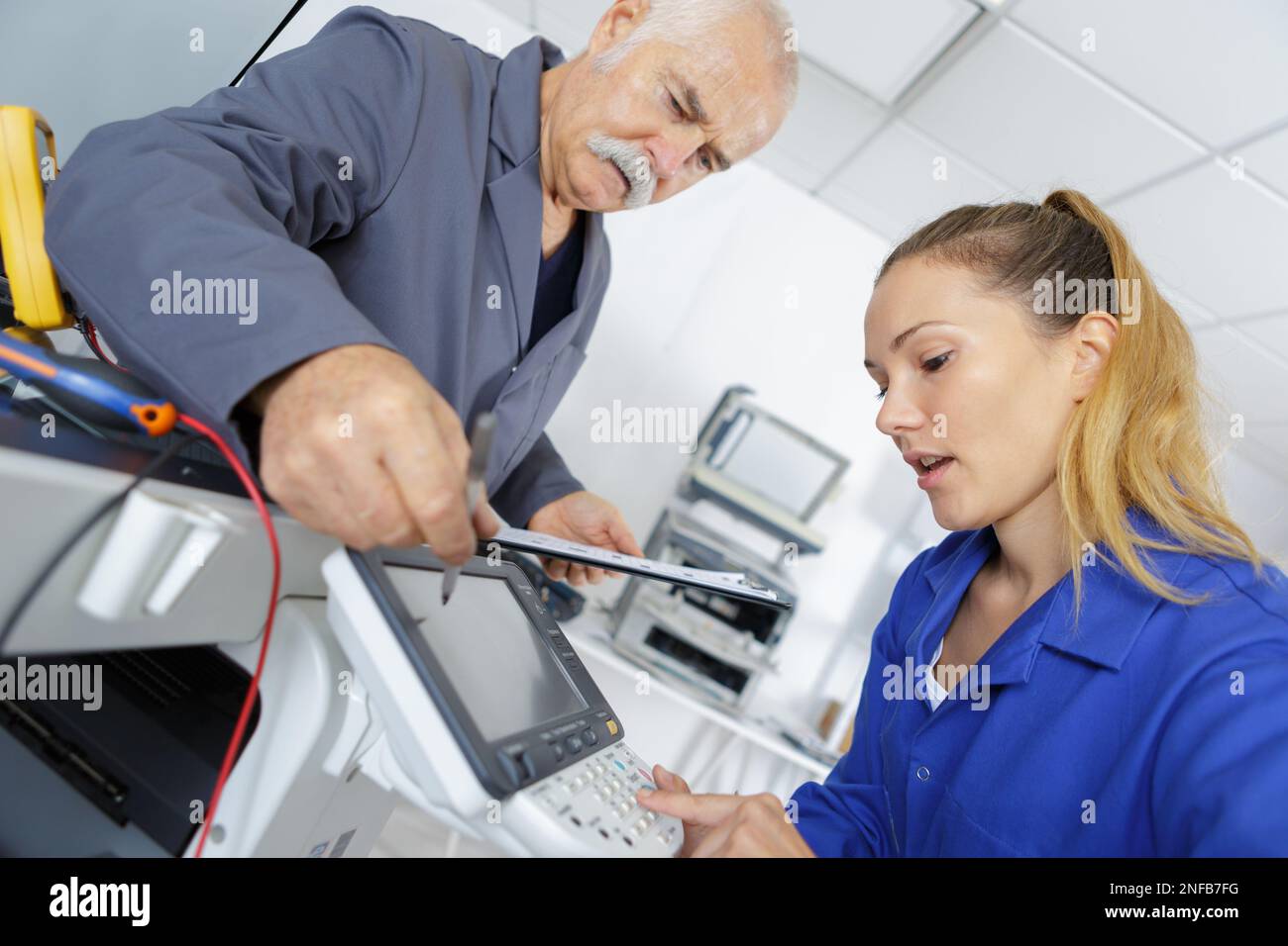 senior man and young woman technician fixing a printer Stock Photo - Alamy