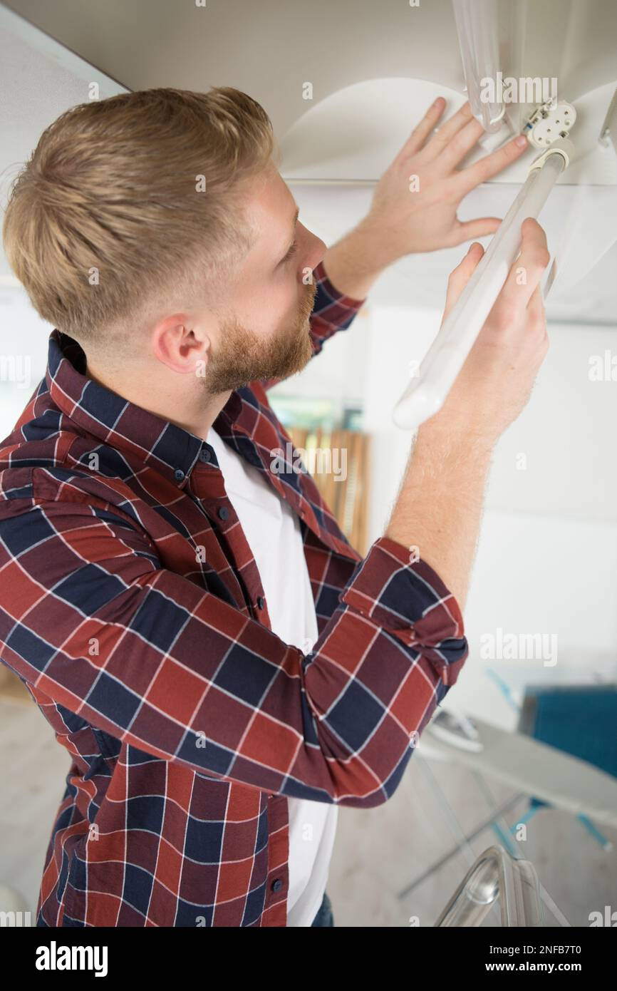 male worker replaces a broken neon light Stock Photo - Alamy