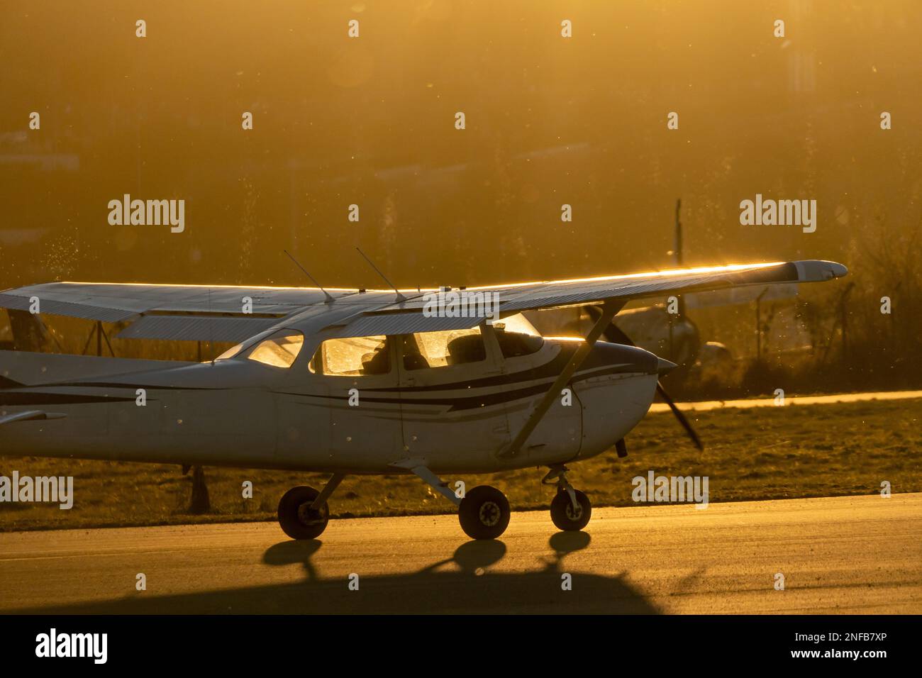 A small propeller plane rolling down the runway in backlight under a ...