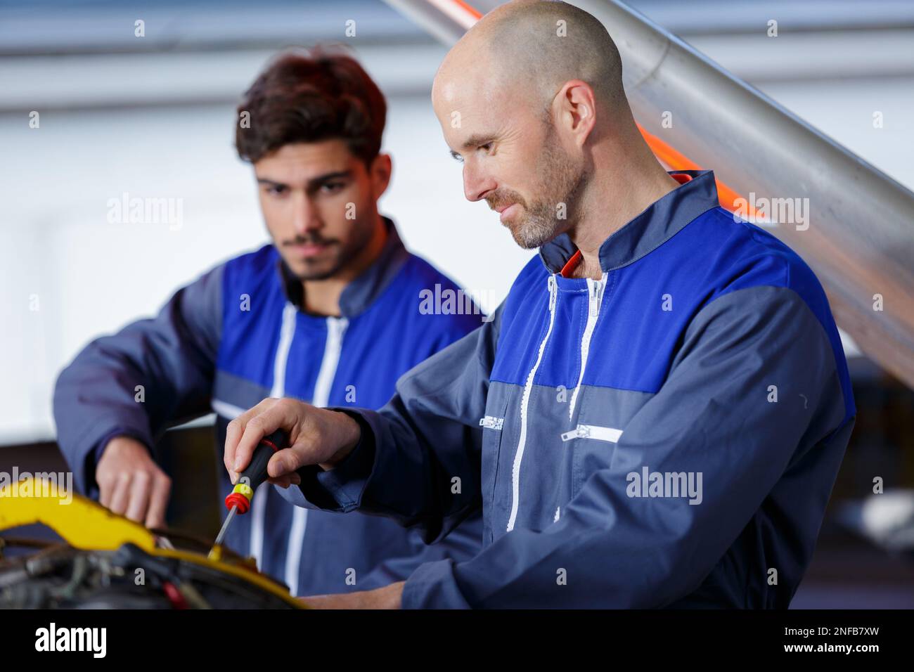 handsome mechanics in uniform are repairing car engine Stock Photo - Alamy