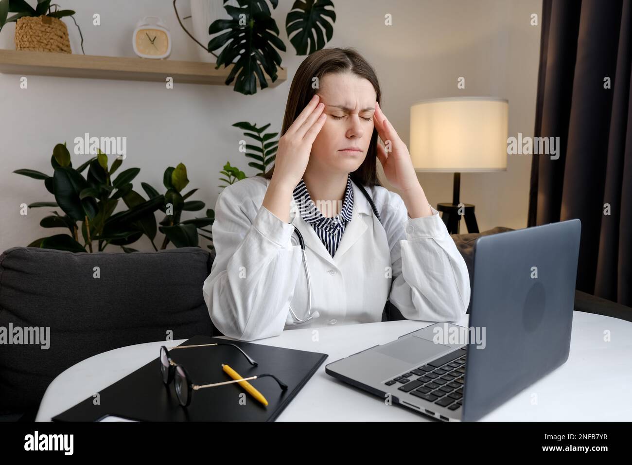 Upset young female doctor wearing white coat and stethoscope coping ...