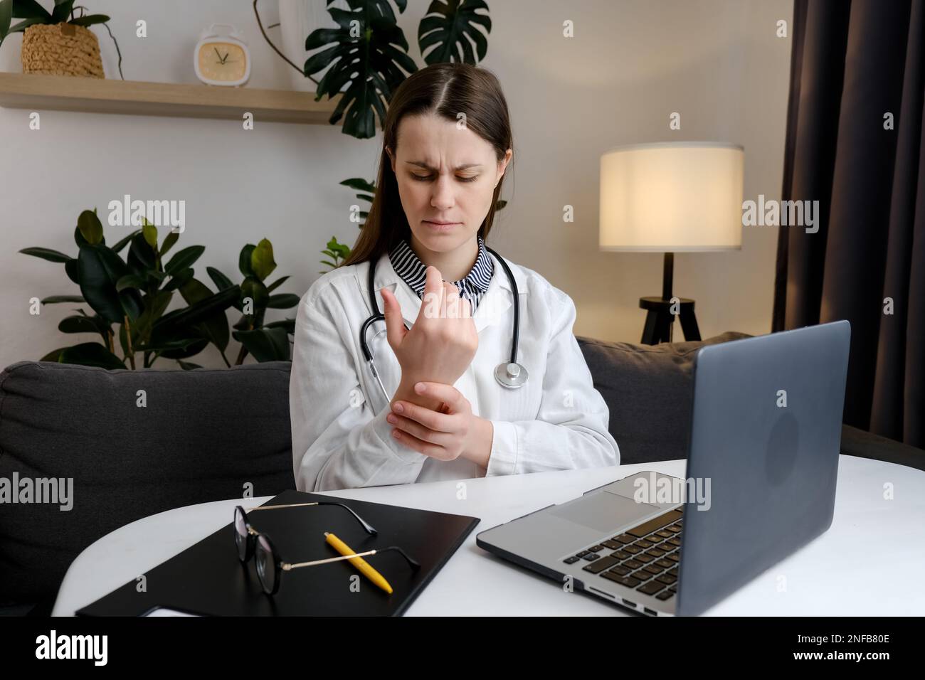 Tired doctor at computer experiences pain and discomfort in hands ...