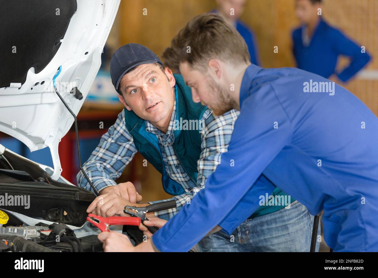 young mechanic learning how to use jump leads Stock Photo - Alamy