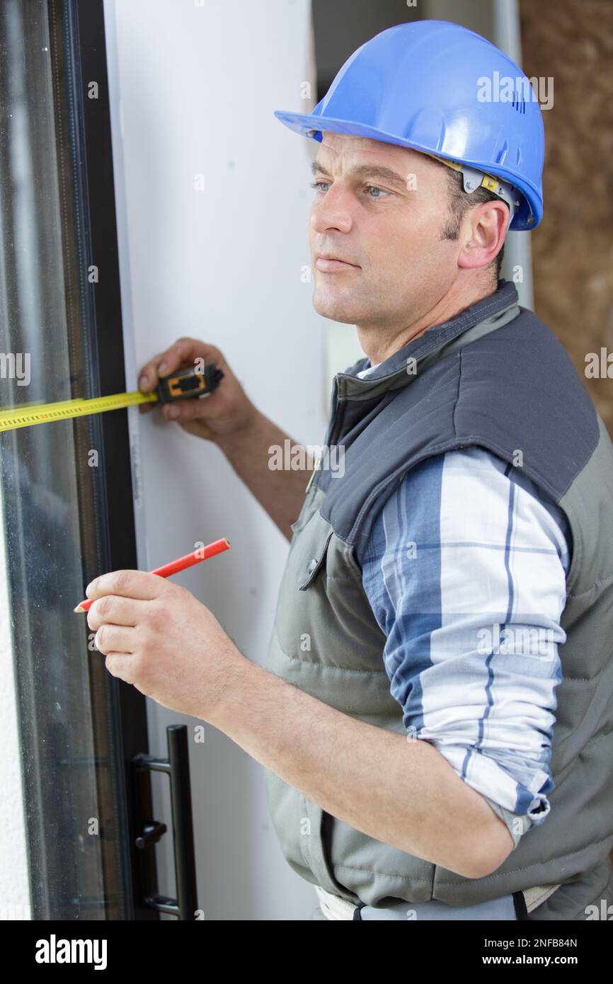 service man measuring window for installation indoors Stock Photo - Alamy