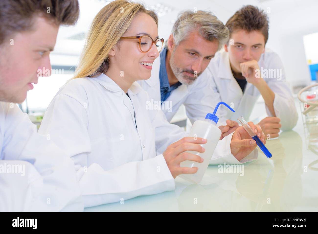 Student squeezing solution from bottle into test tube Stock Photo - Alamy
