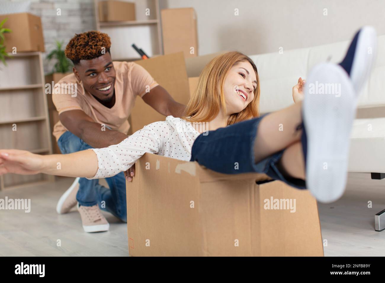 man pushing laughing wife in carton box Stock Photo - Alamy