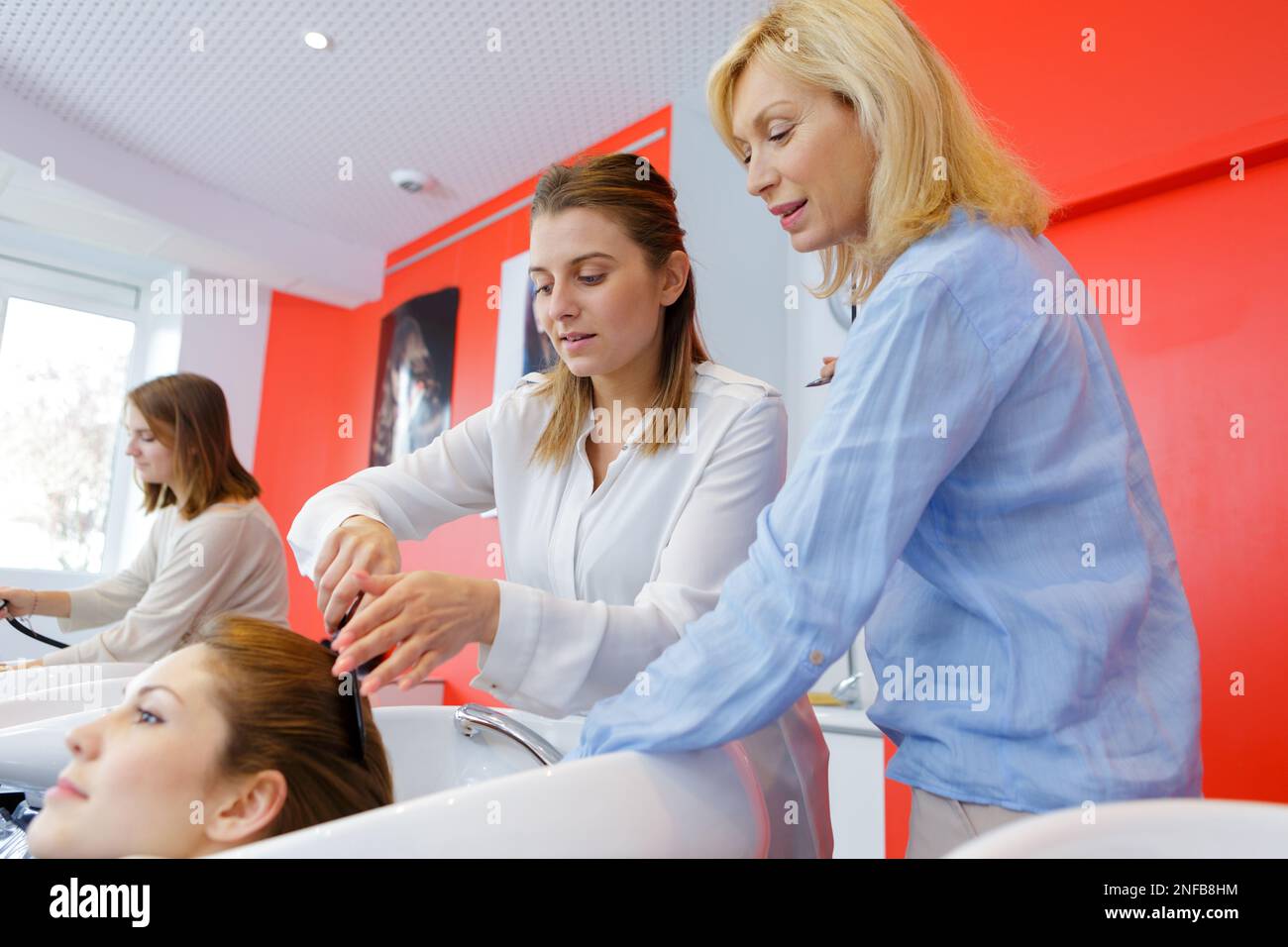 trainee hairdresser washing female clients hair under supervision Stock ...
