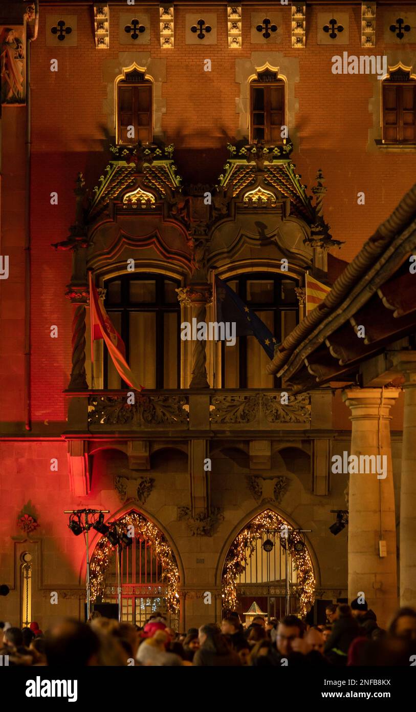 The colorfully illuminated facade of the town hall with a large group ...