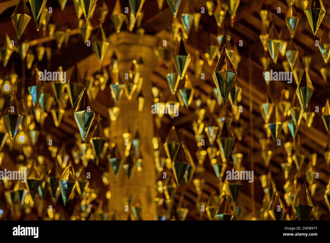 Diamonds or golden geometric shapes hanging from the wooden ceiling of ...