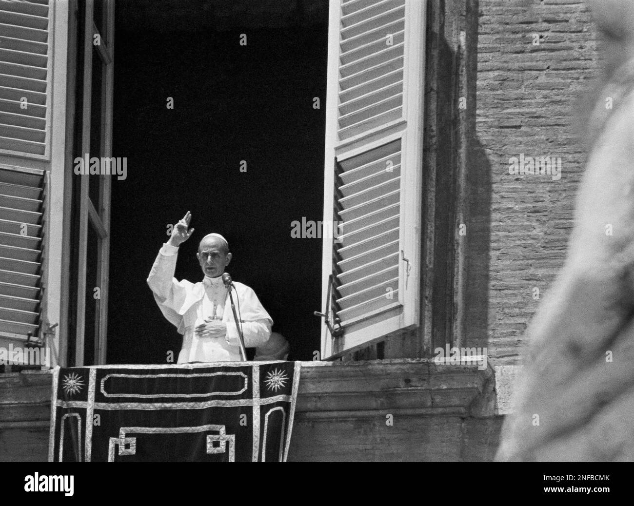 His arm raised in a sign of blessing, Pope Paul VI stands in a window ...