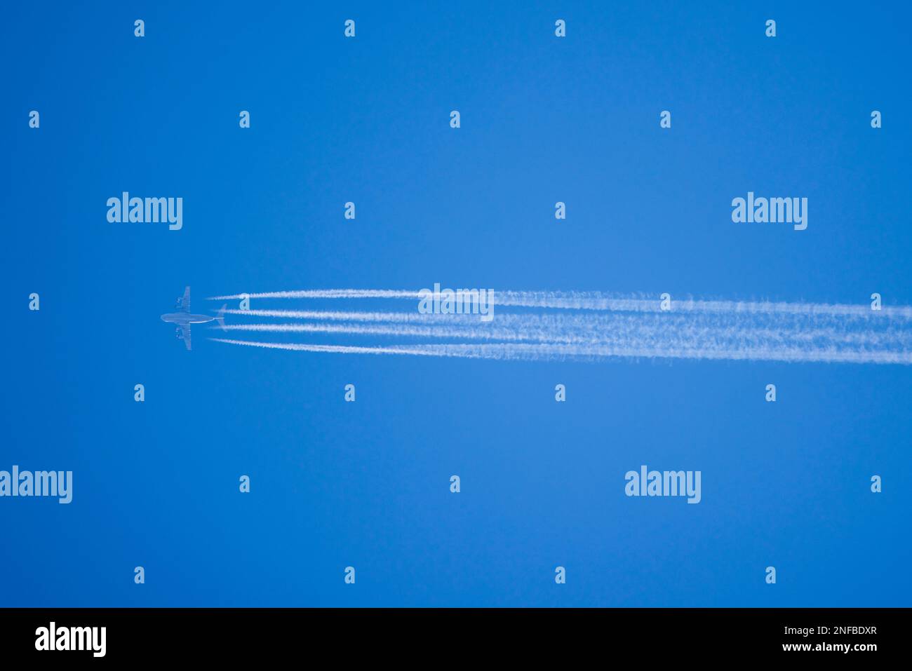 Airplane In Blue Sky With Plane Trails Stock Photo - Alamy