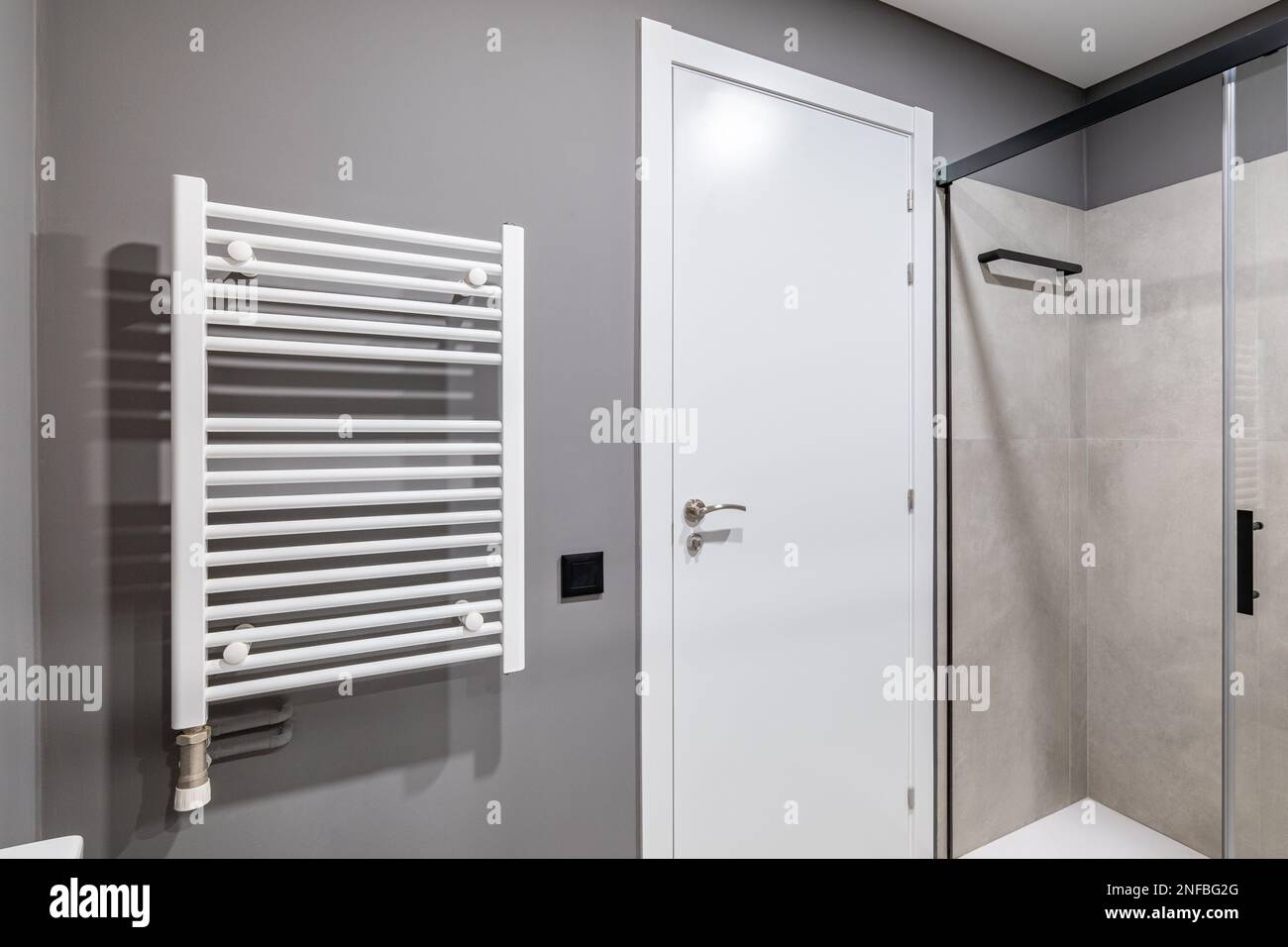 Part of a bathroom with a gray wall. White front door with metal handle ...