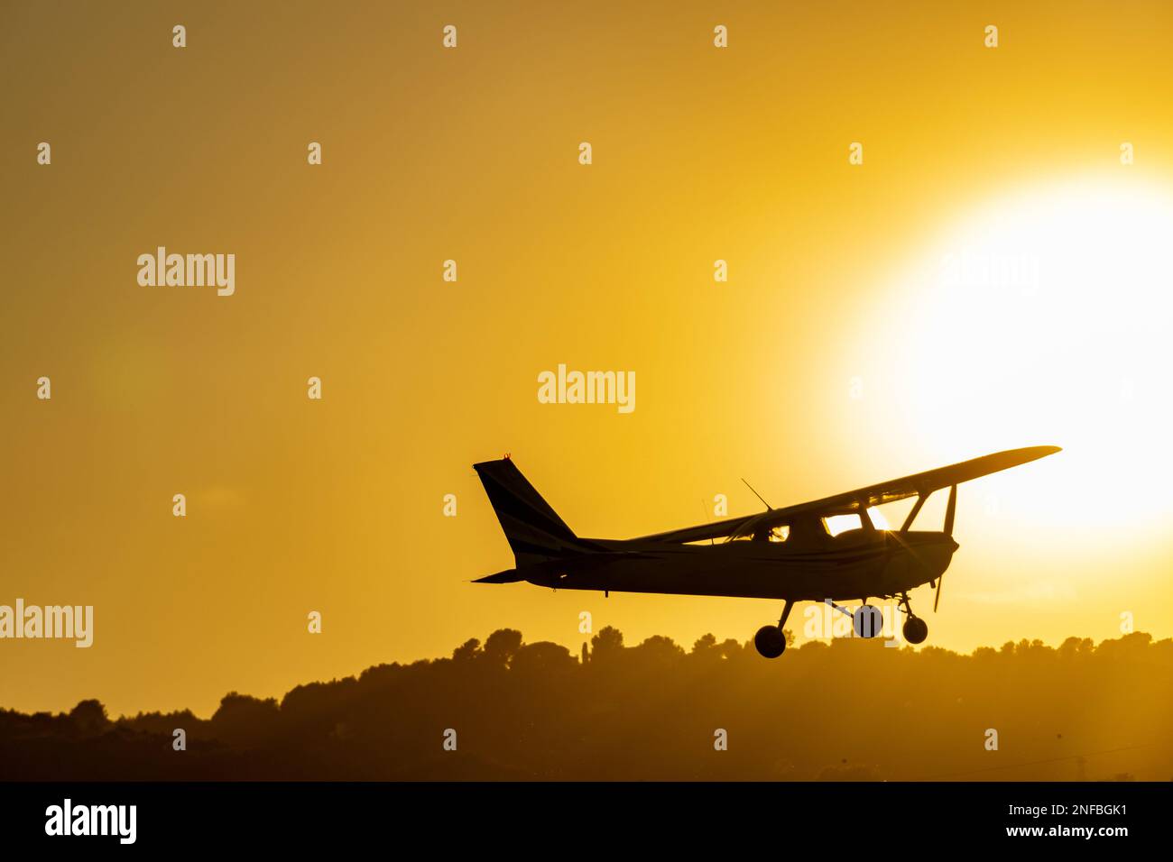 Silhouette of a small propeller plane landing or taking off on the ...