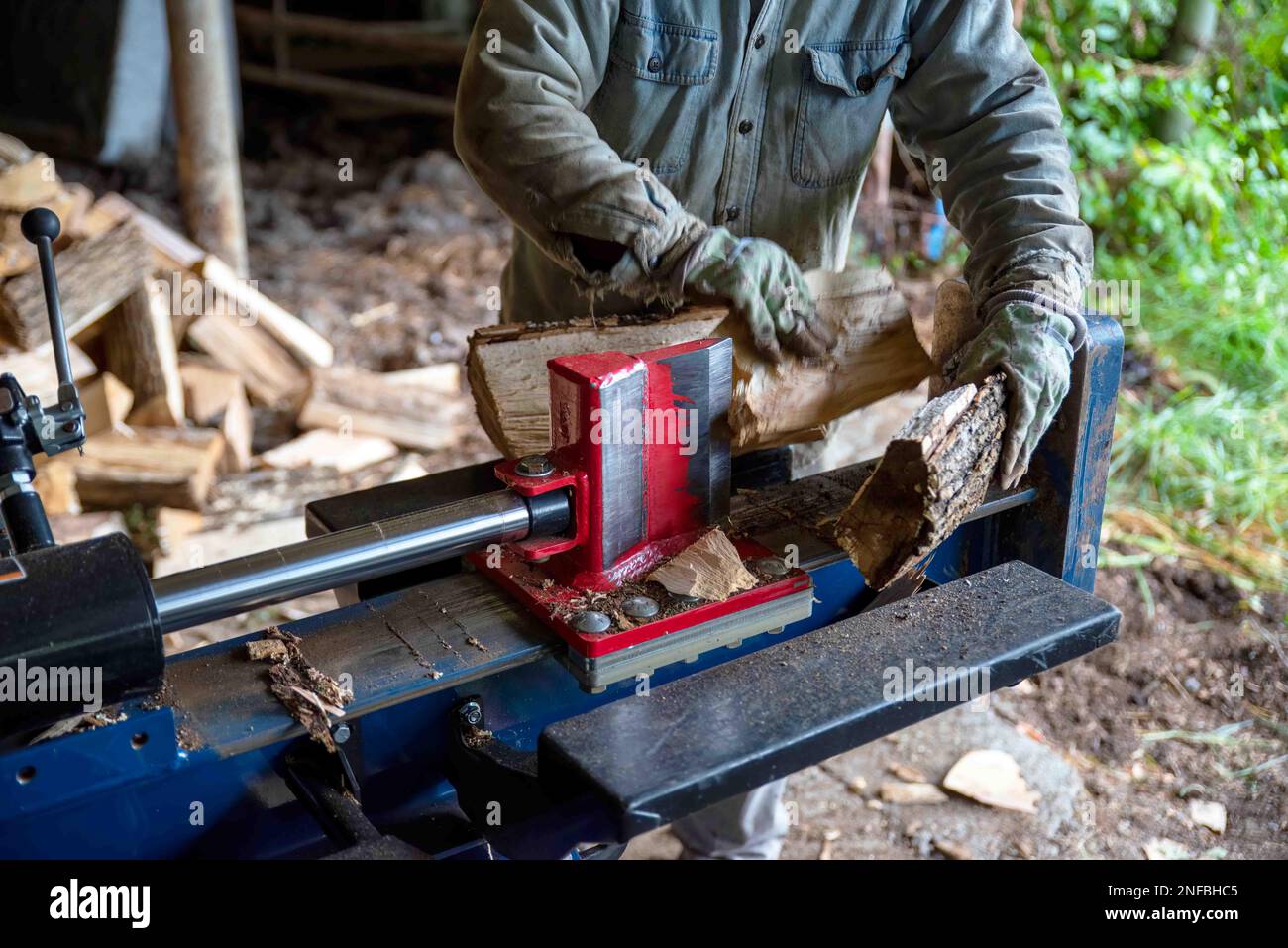 Caucasian senior man splits wood with a hydraulic log splitter in a ...
