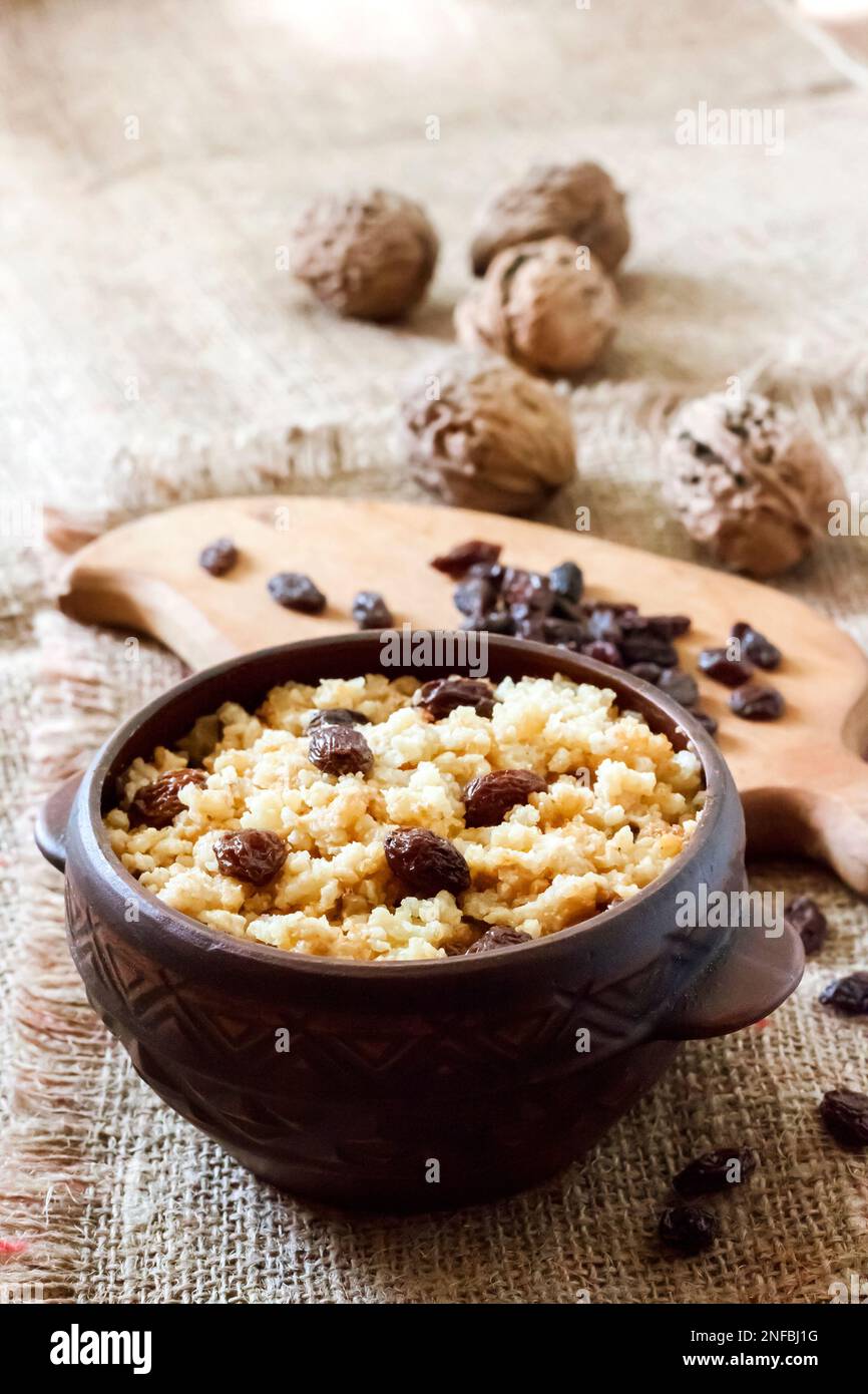 Sweet millet porridge with dark raisins in ceramic rustic bowl with ...