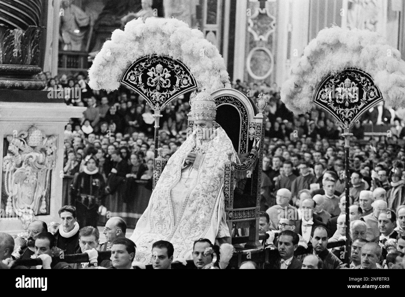 Pope John XXIII, wearing the triple-crowned tiara of the papacy sits on ...