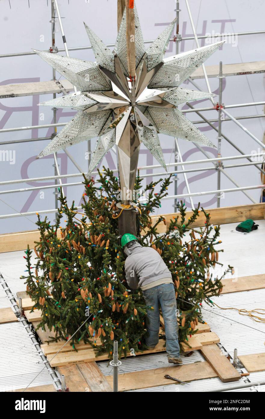 A worker secures a guy-wire to the top of the 72-foot tall Rockefeller ...