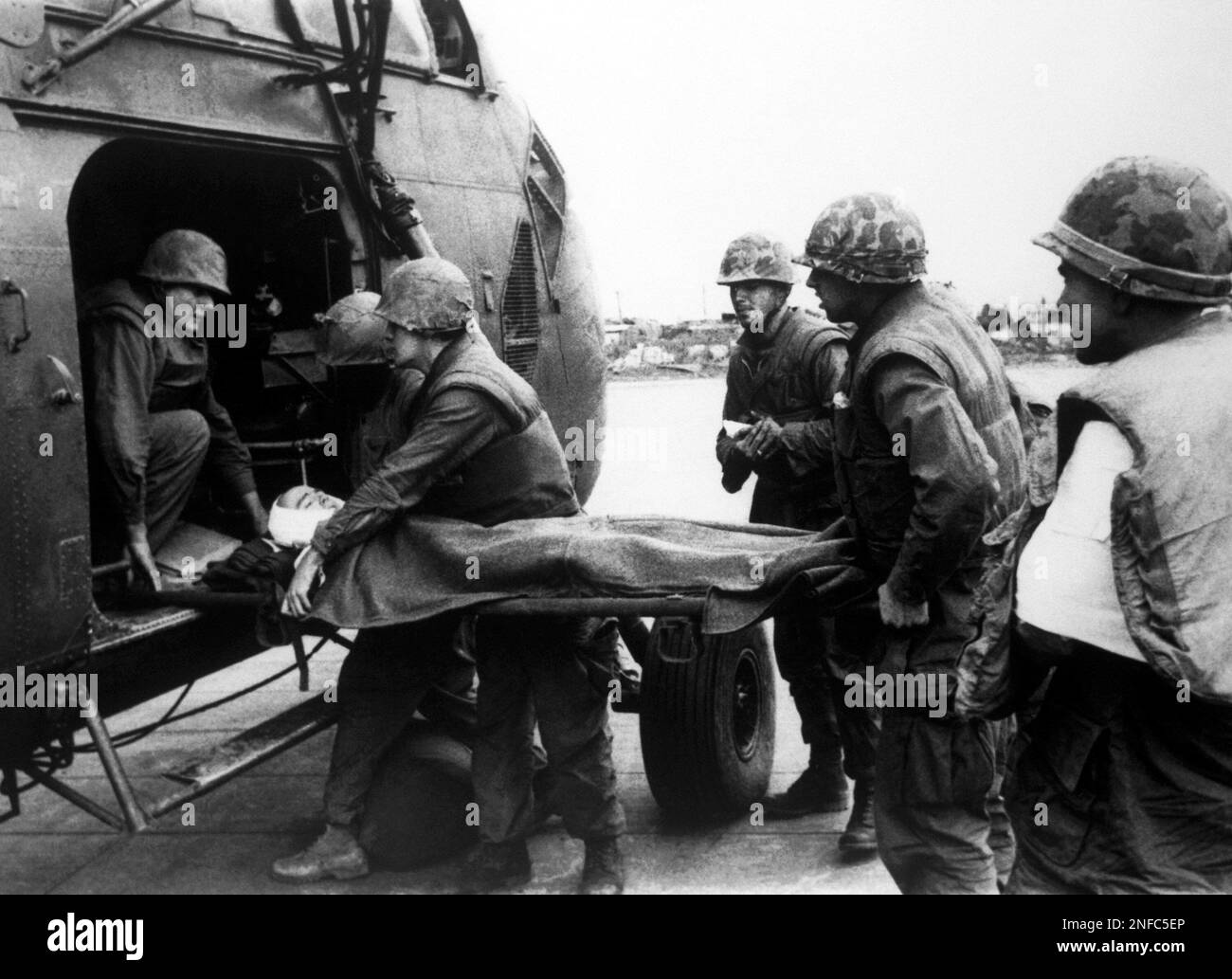 American soldiers hustle a wounded comrade aboard a helicopter at Khe ...