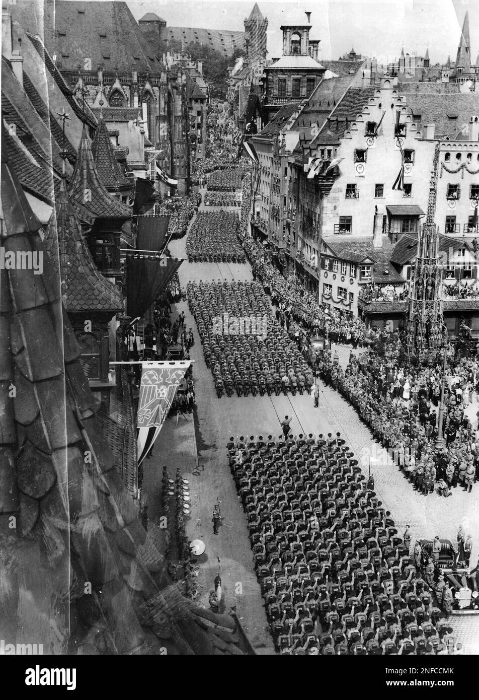 Thousands of SA members march past Adolf Hitler, saluting, standing in ...