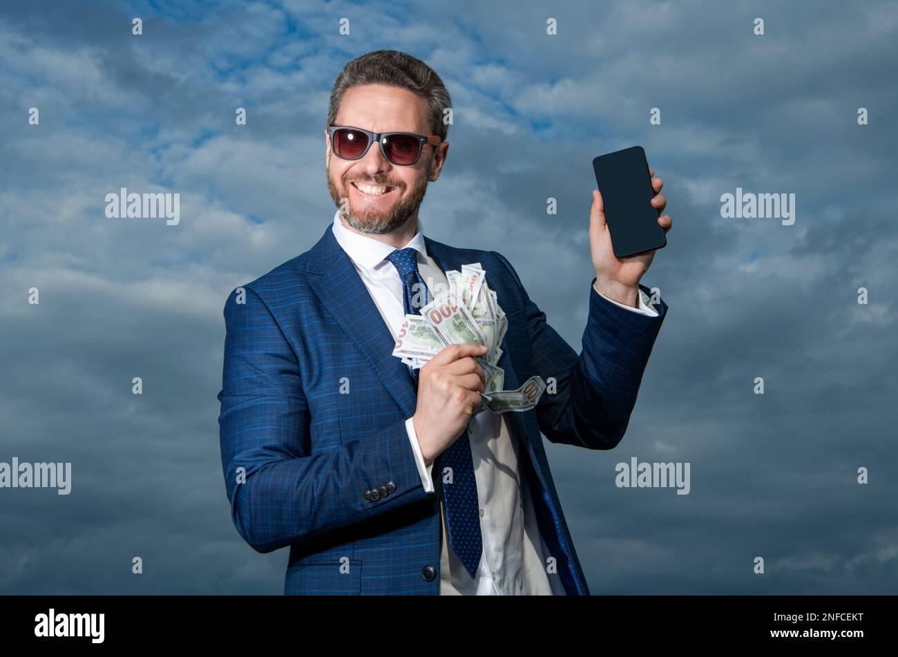 Happy successful rich man banker holding cash money showing mobile ... Happy successful rich man banker holding cash money showing mobile ...