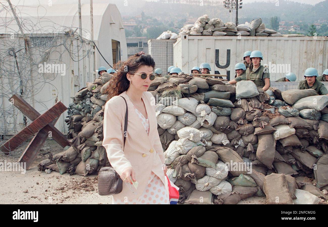 A Sarajevan woman walks past French United Nations soldiers preparing ...